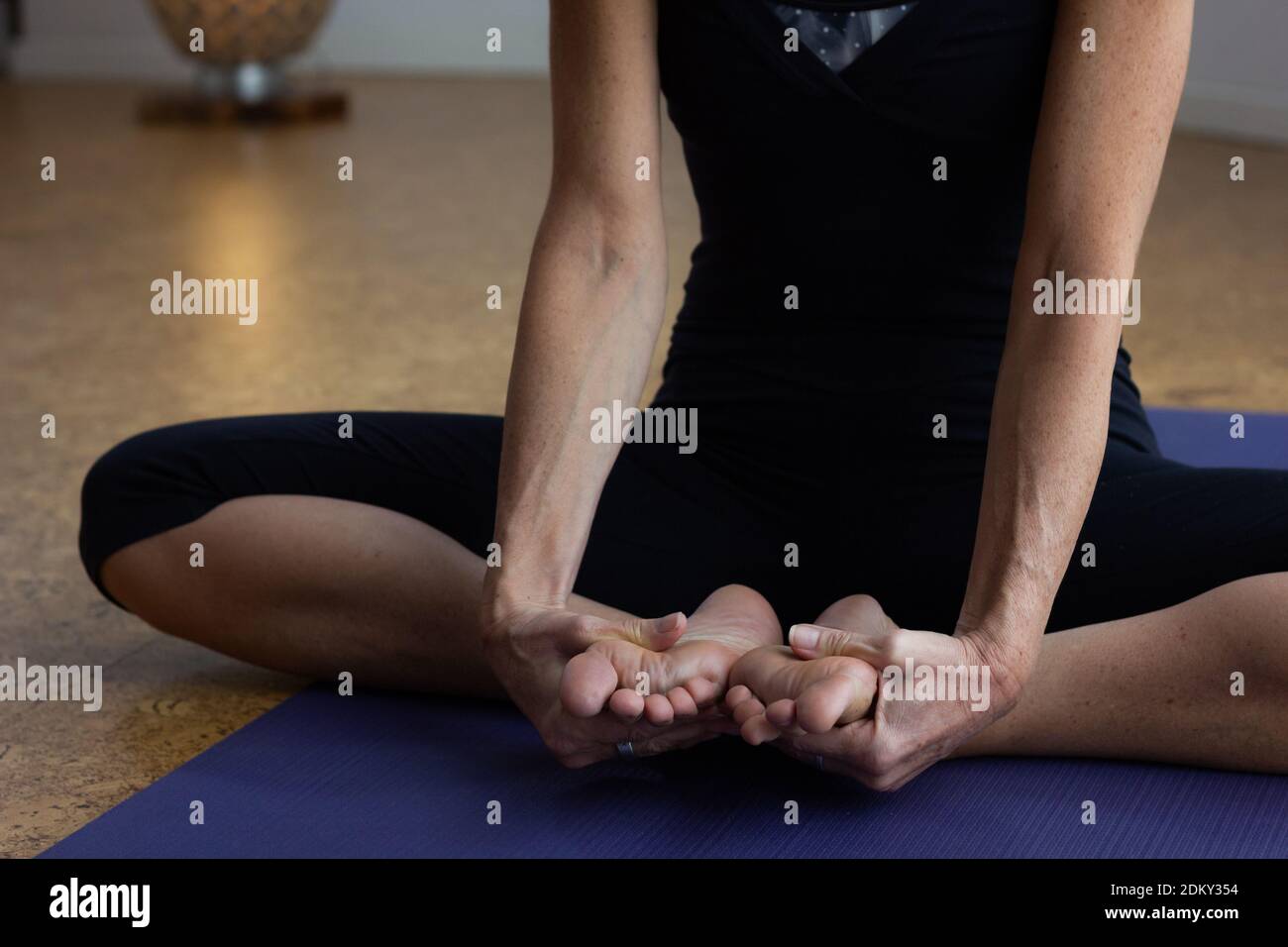 Body of female yogi sitting with hands holding feet together in bound ...
