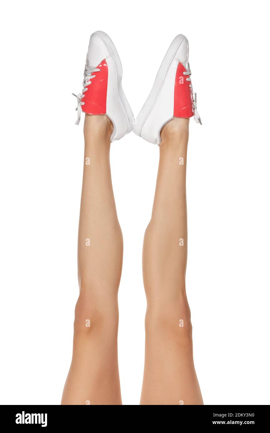 Close-up slim female legs in white footwear isolated over studio ...