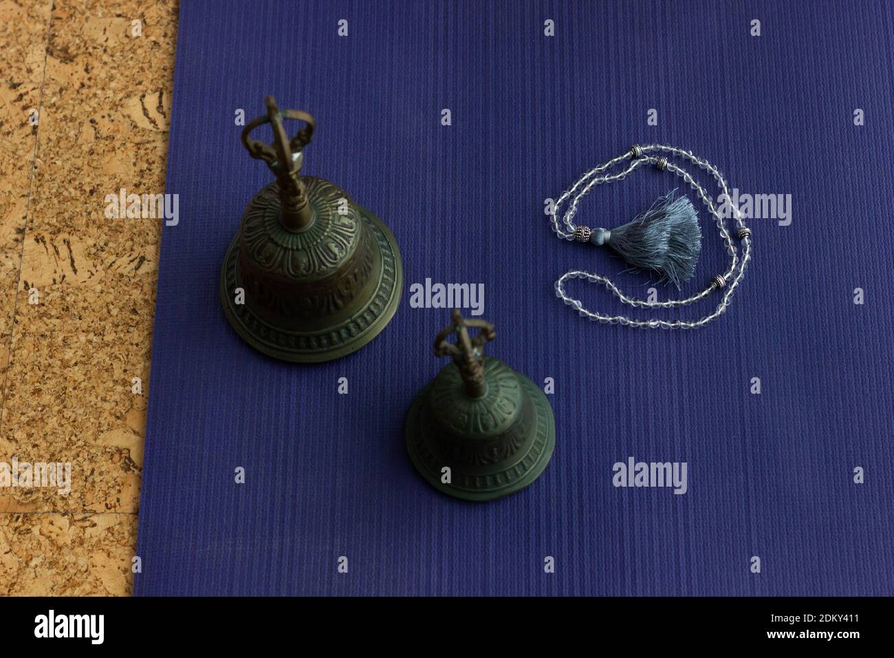 Metal bells on yoga mat with mala necklace on side. Top view of ...