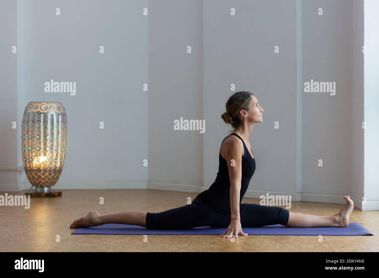 Flexible woman with split legs on monkey pose at studio. Middle aged ...