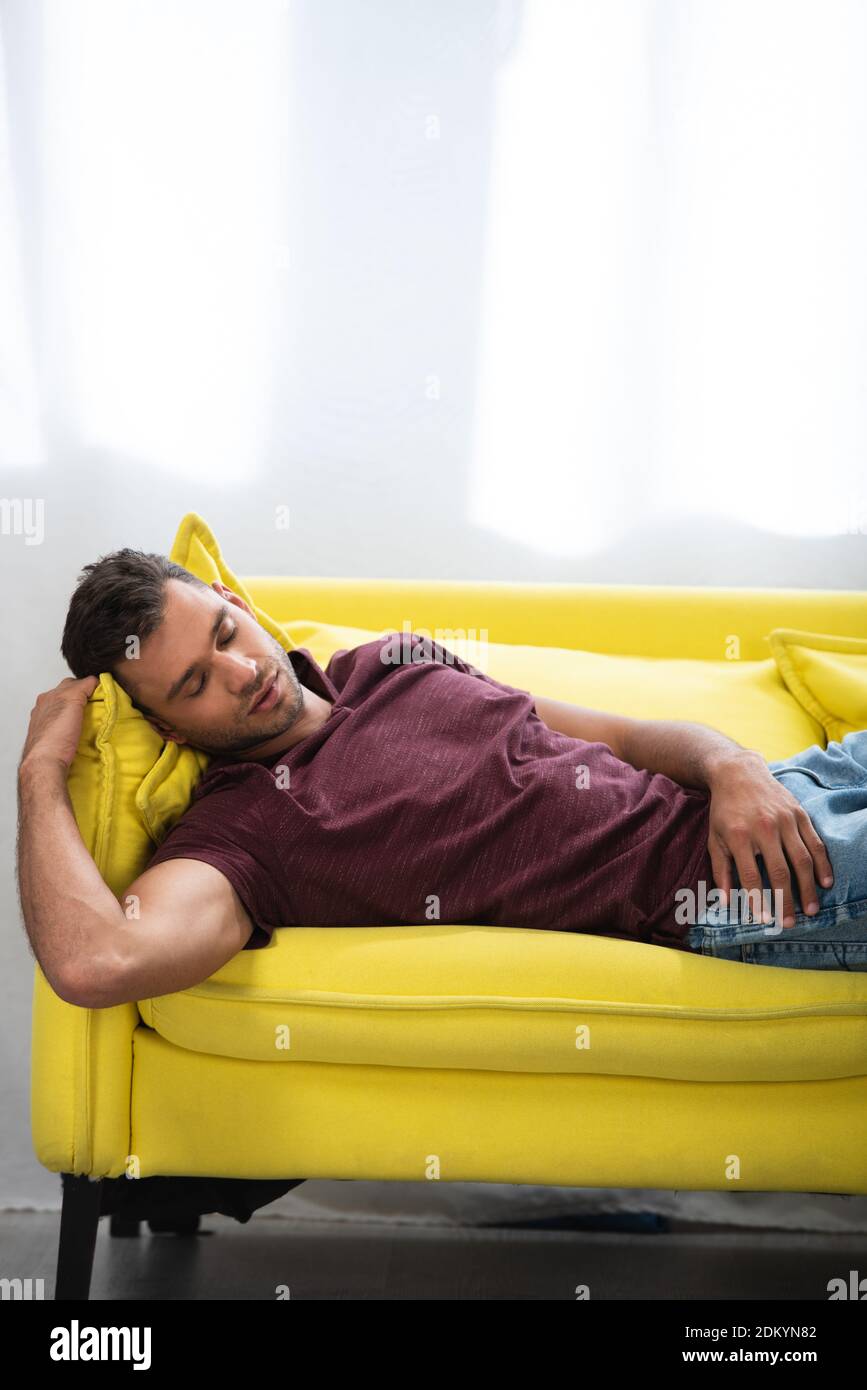 Man sleeping on yellow sofa at home Stock Photo - Alamy
