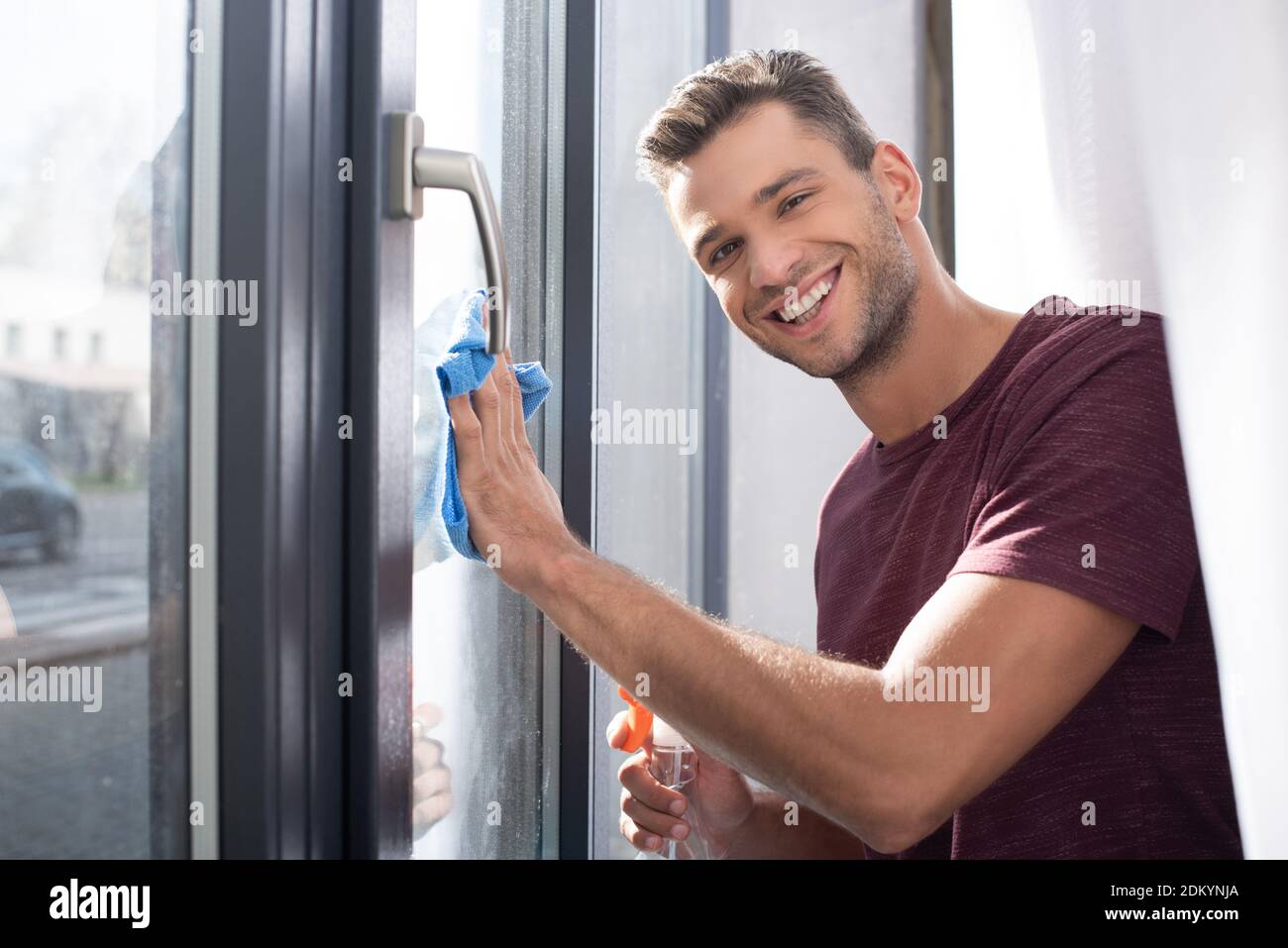 Smiling man cleaning window with rag and detergent at home Stock Photo ...
