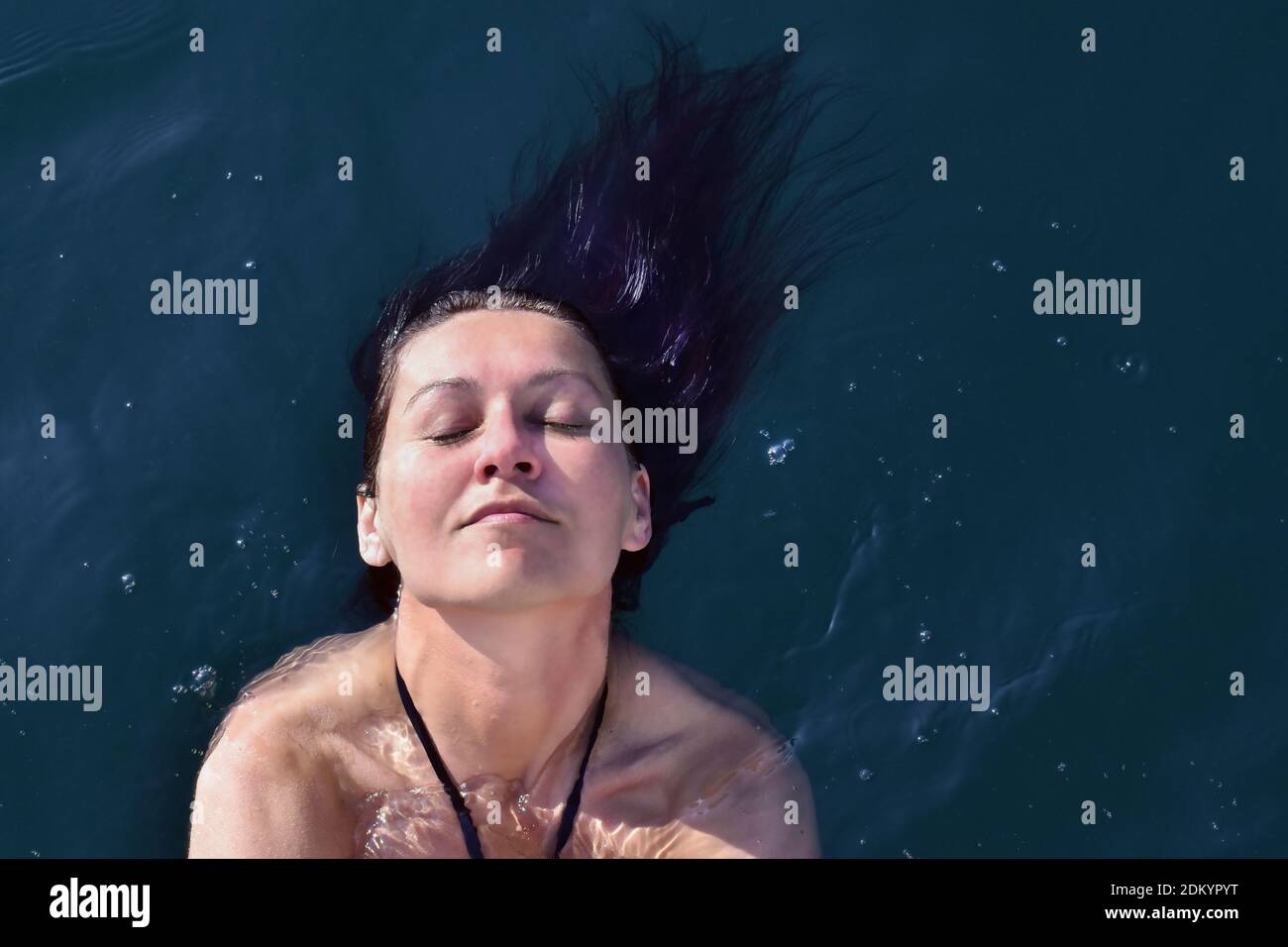 Head shot taken from a boat of relaxed young woman enjoying bathing in ...