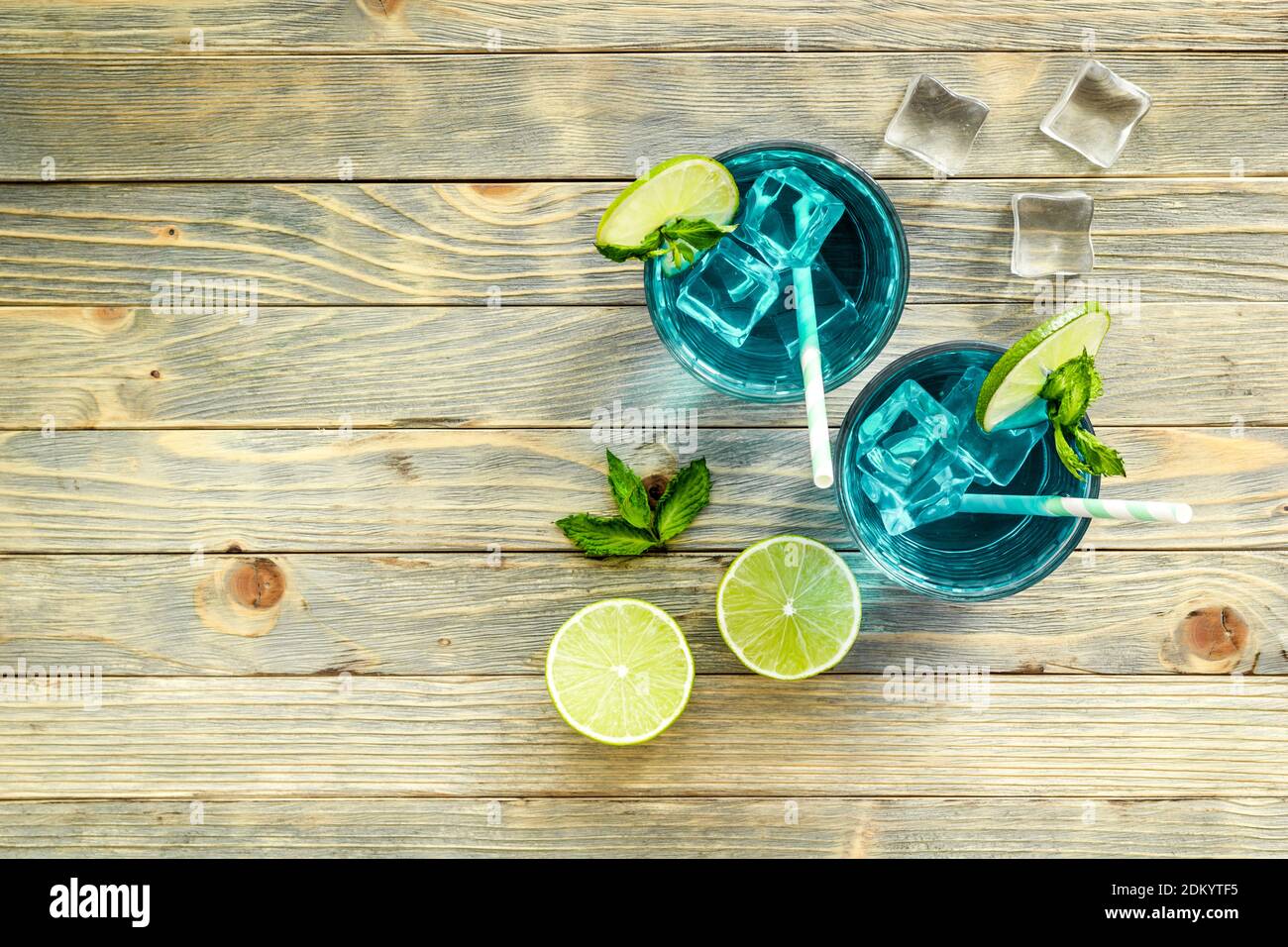 Blue beverage, iced alcohol cocktail drink with lime and mint, top view ...