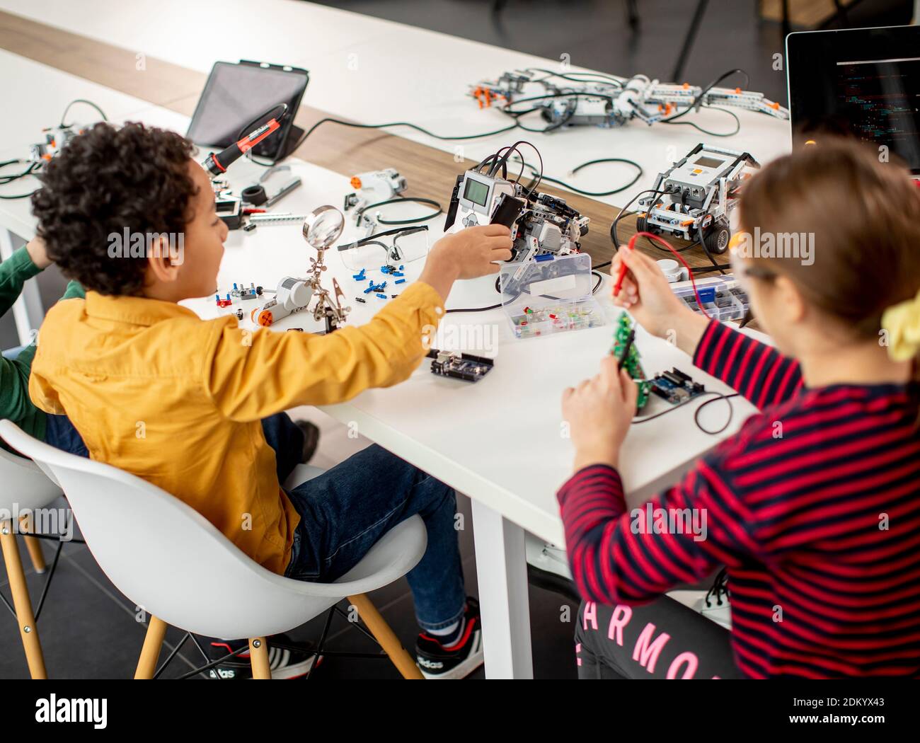Group of happy kids programming electric toys and robots at robotics ...