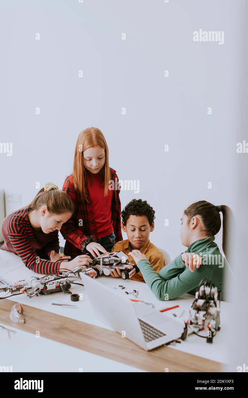 Group of happy kids programming electric toys and robots at robotics ...