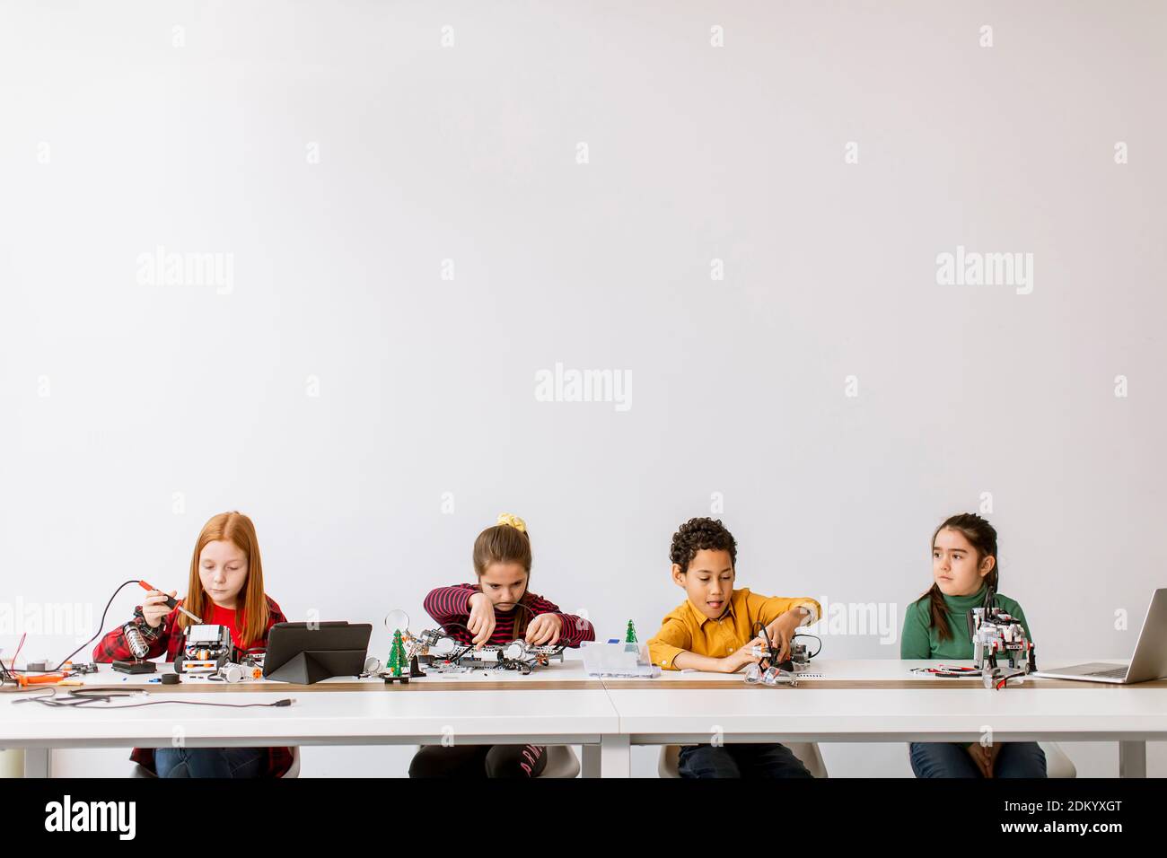 Group of happy kids programming electric toys and robots at robotics ...