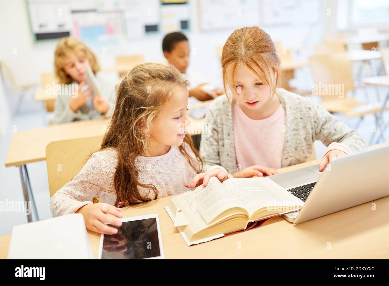 Four school girls reading book table hi-res stock photography and ...