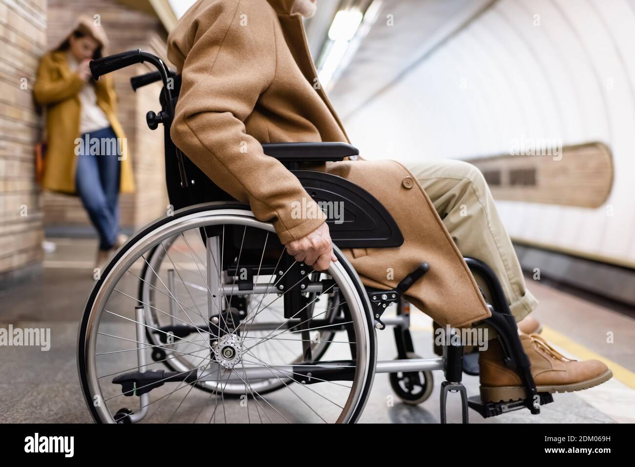 side view of elderly disabled man on metro platform, and woman on ...