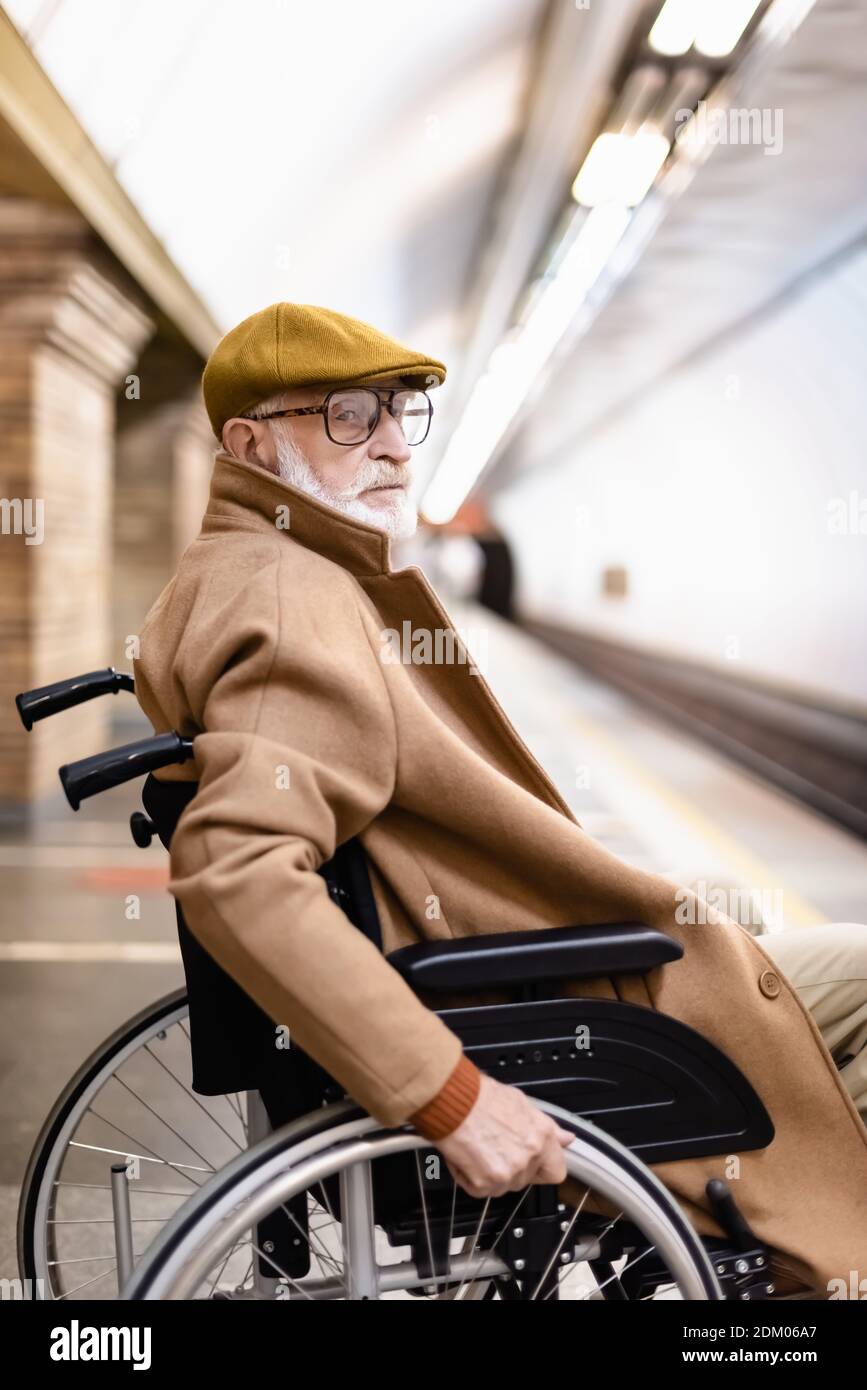 aged disabled man in autumn coat and cap sitting in wheelchair on ...