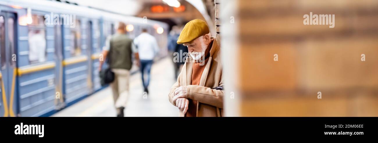 senior man in autumn outfit standing on metro platform with train and ...