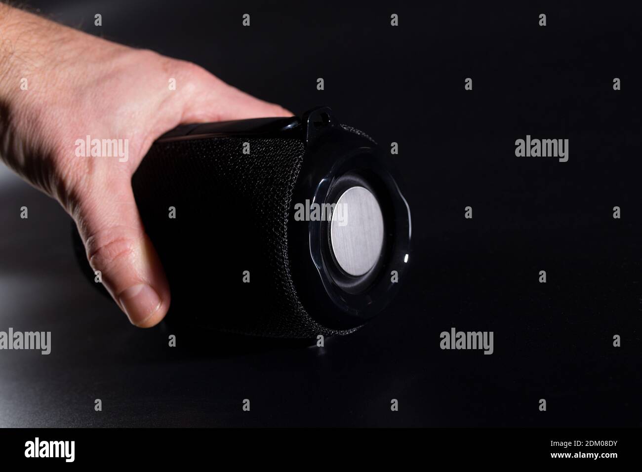 Hand holding wireless portable speaker on black background with copy ...