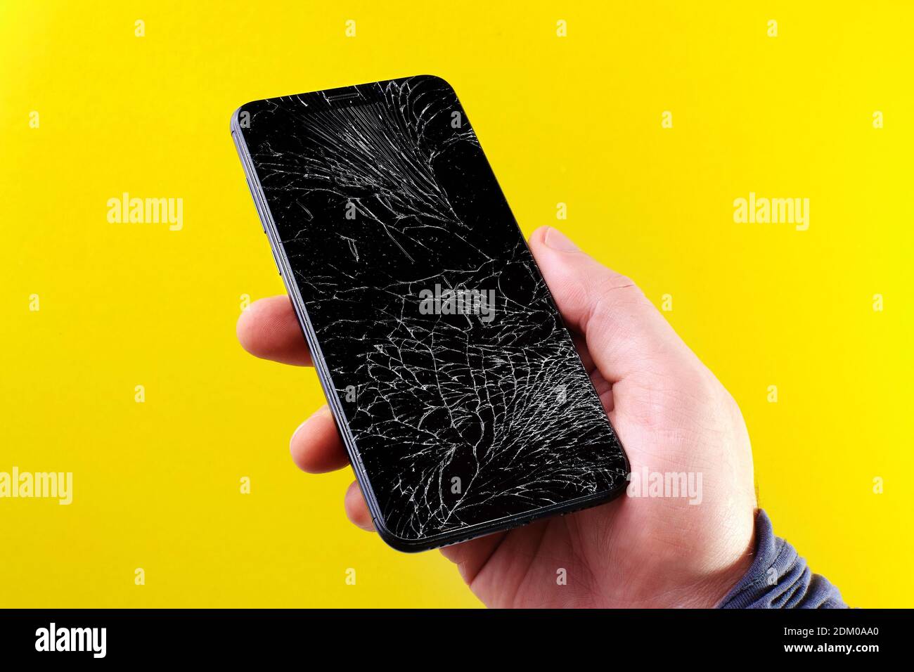 Black smartphone with a broken touch screen in hand on a yellow ...