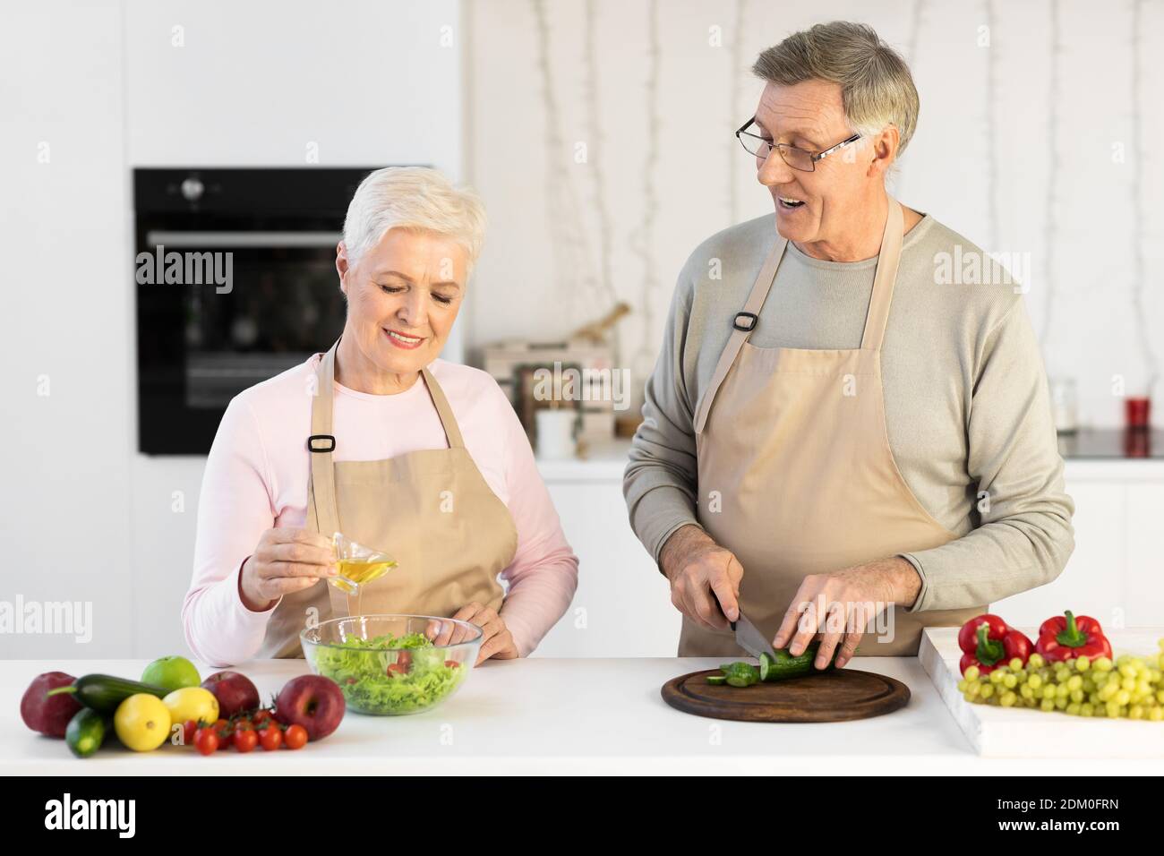 Senior Couple Enjoying Food Preparation Cooking In Modern Kitchen ...