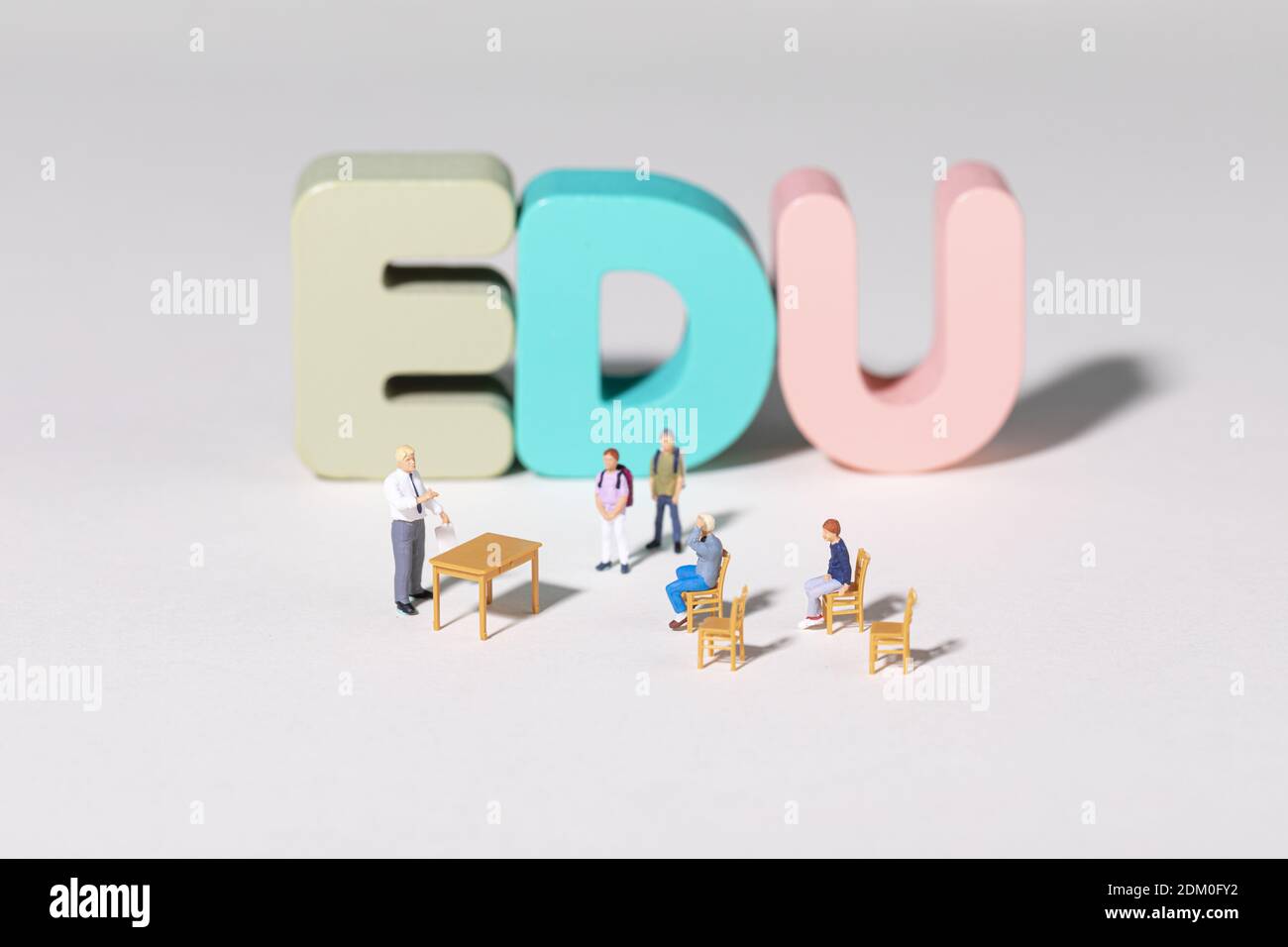 A high angle shot of teacher and student figurines standing around EDU ...