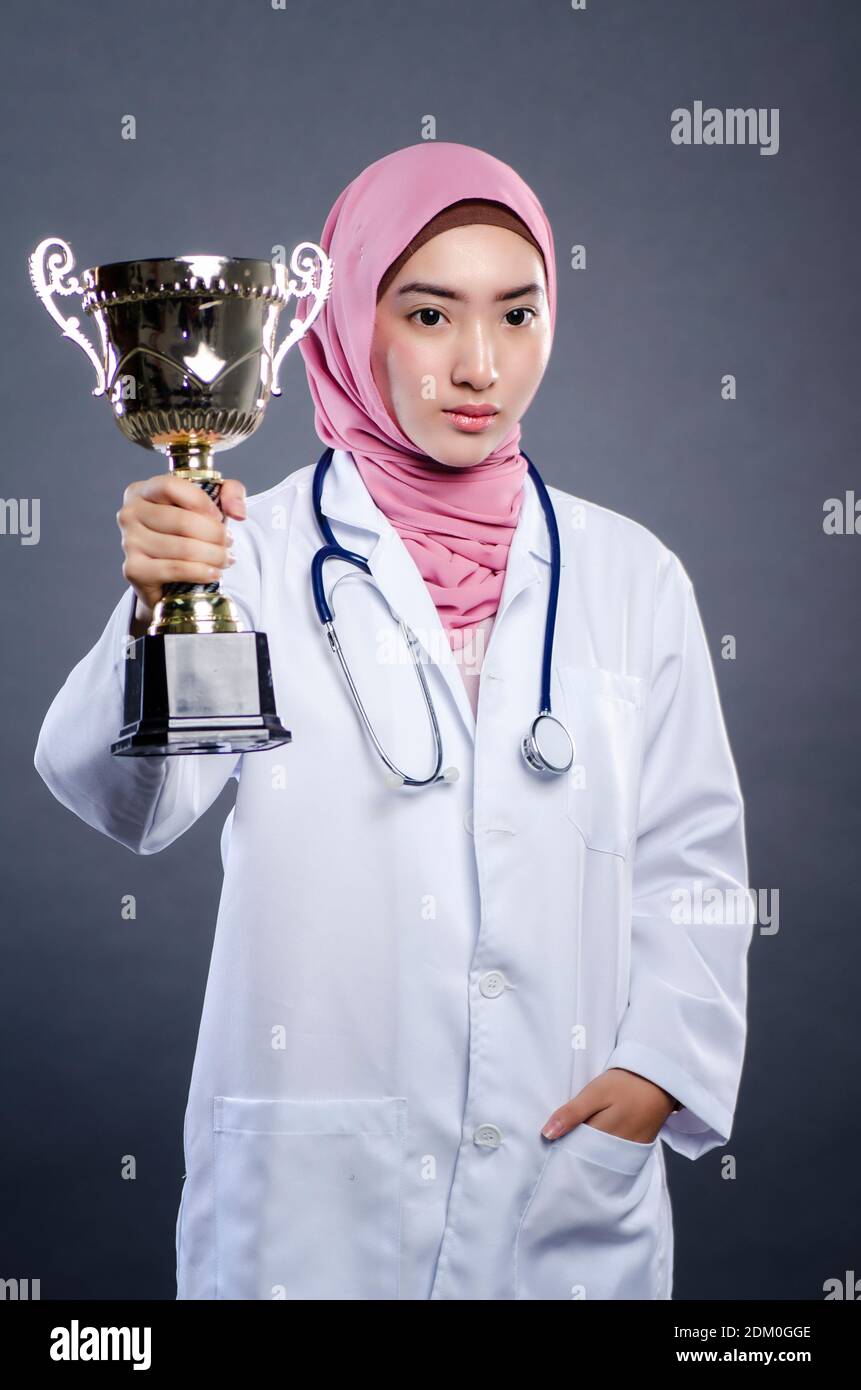 Portrait Of Doctor Holding Trophy While Standing Against Gray ...