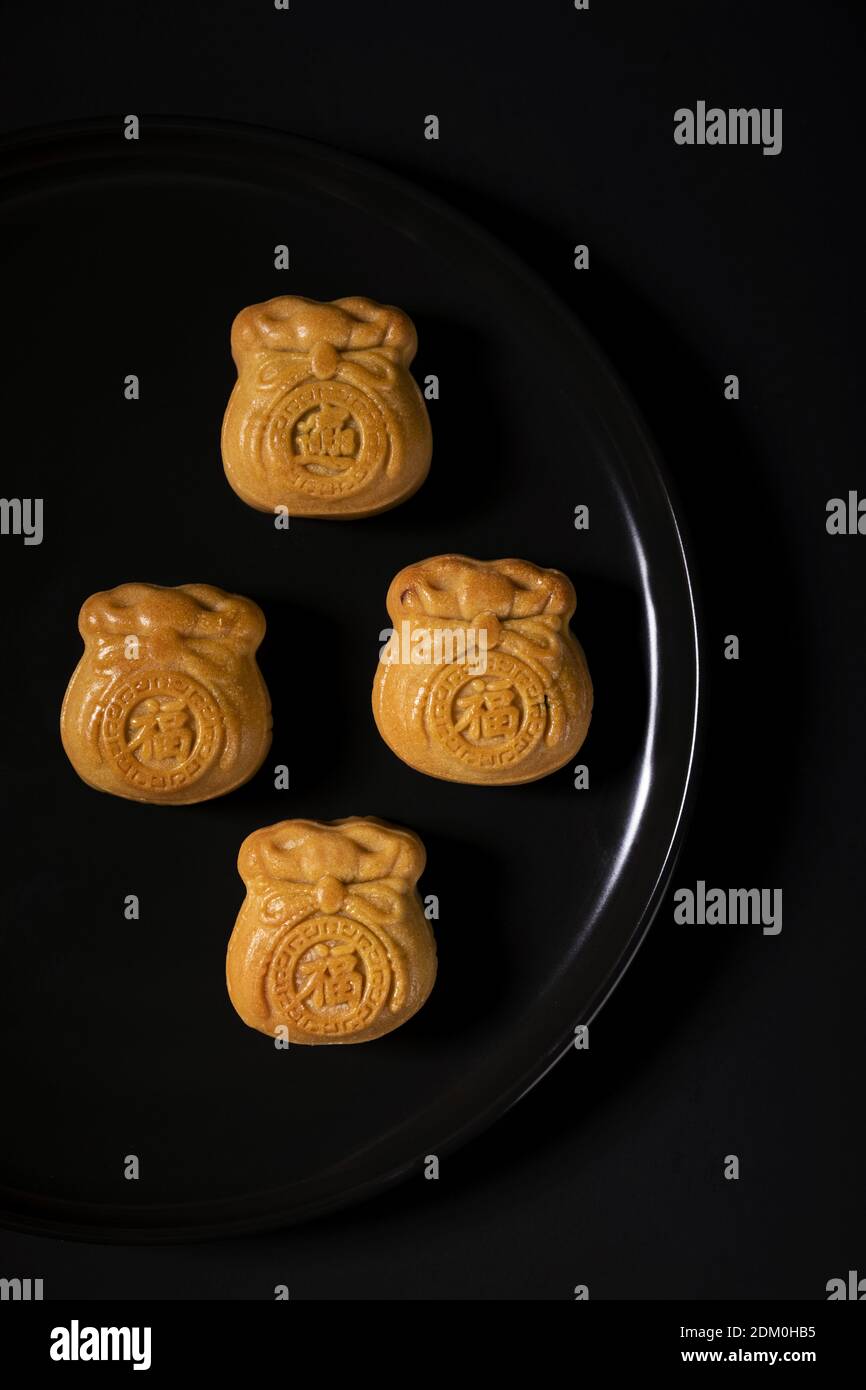 A vertical top view of mooncakes on a black plate for Mid-Autumn ...