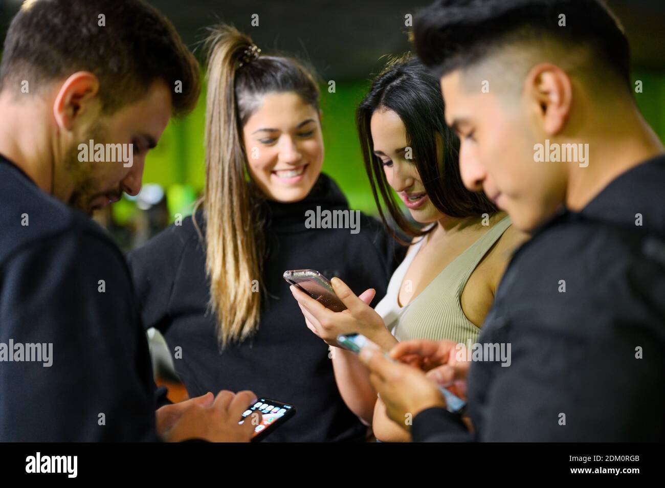 Group of young people using and looking at mobile phone together. High ...