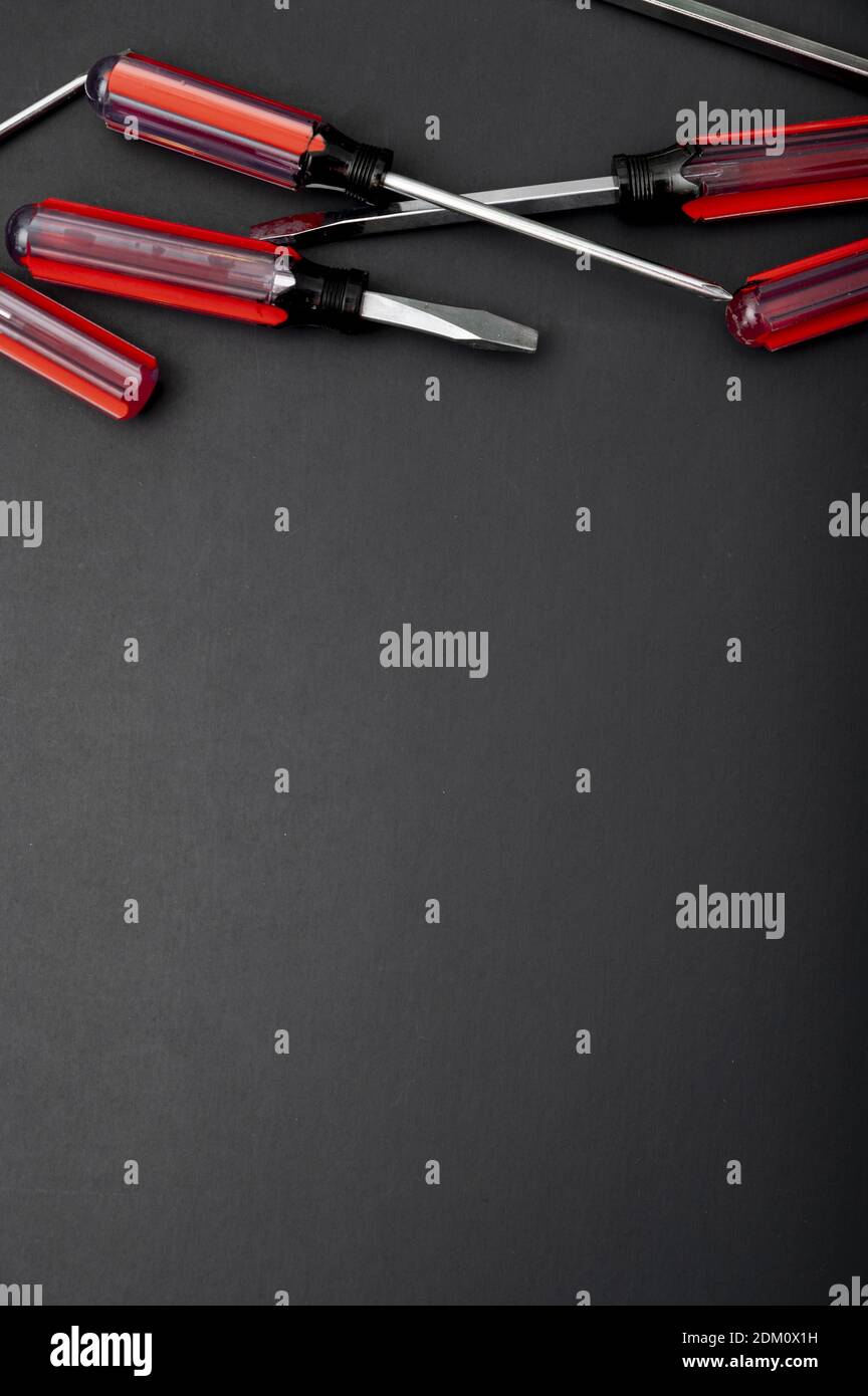A top view of screwdrivers of different sizes on a black background ...