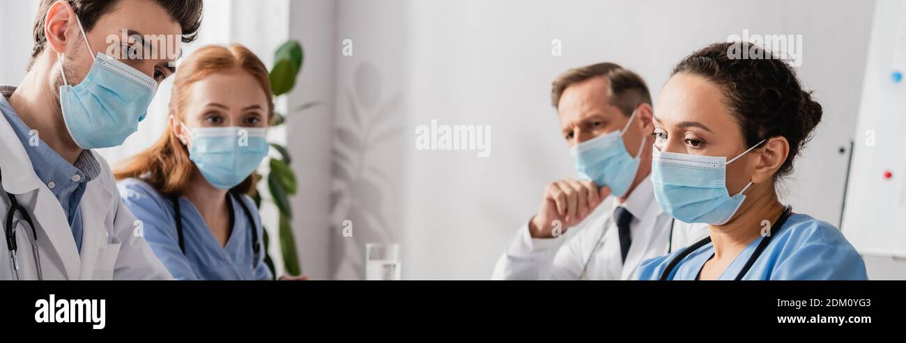 Multiethnic hospital staff in medical masks in hospital on blurred ...