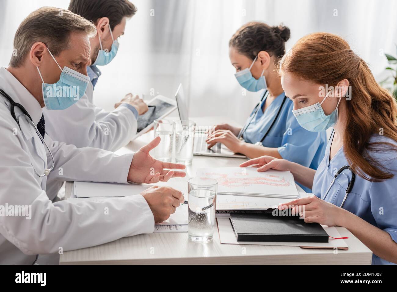 Multiethnic hospital staff working while sitting at workplace with ...