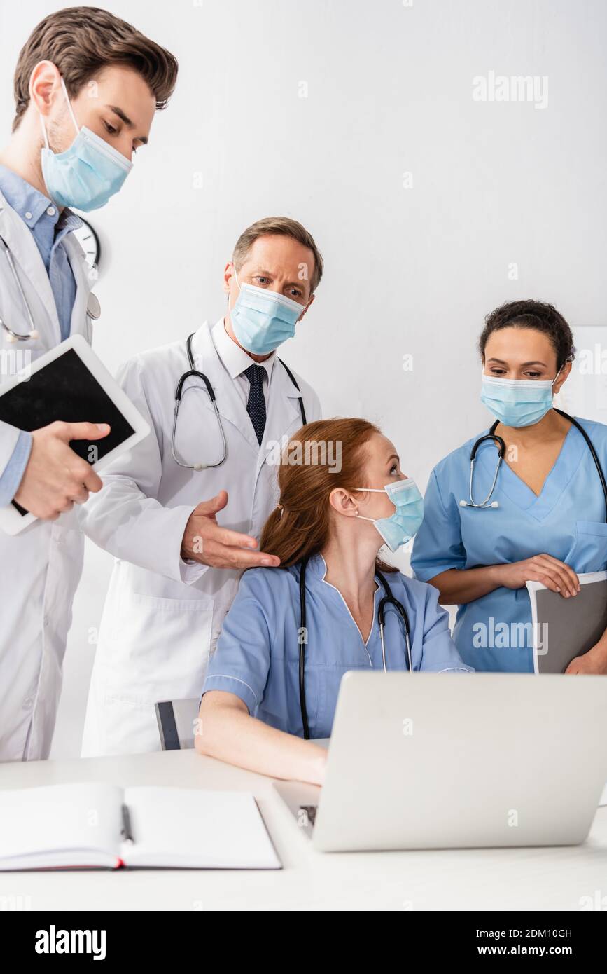 Multicultural nurses and doctors using laptop at workplace on blurred ...