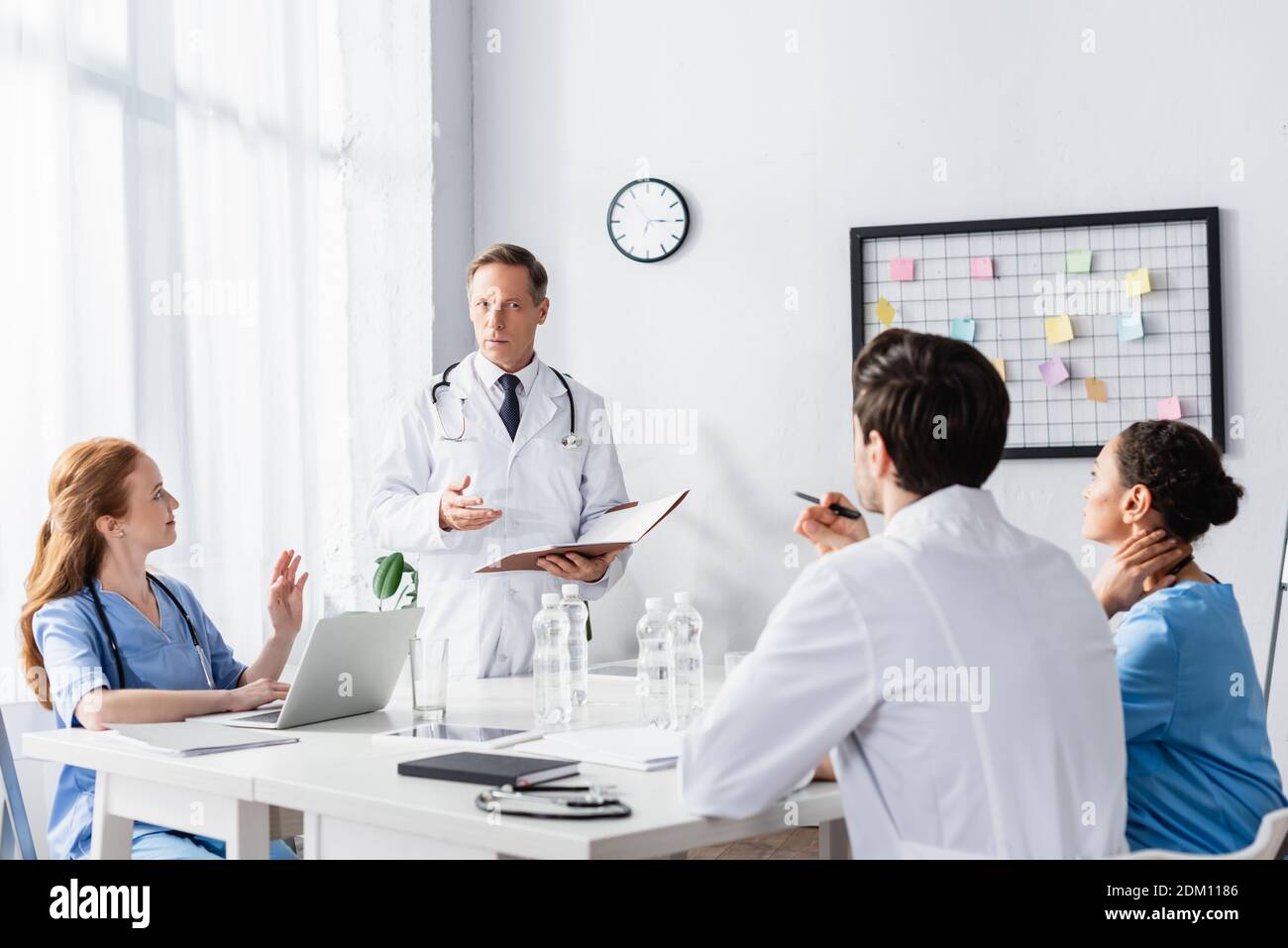 Multiethnic hospital staff working with laptop and paper folder in ...