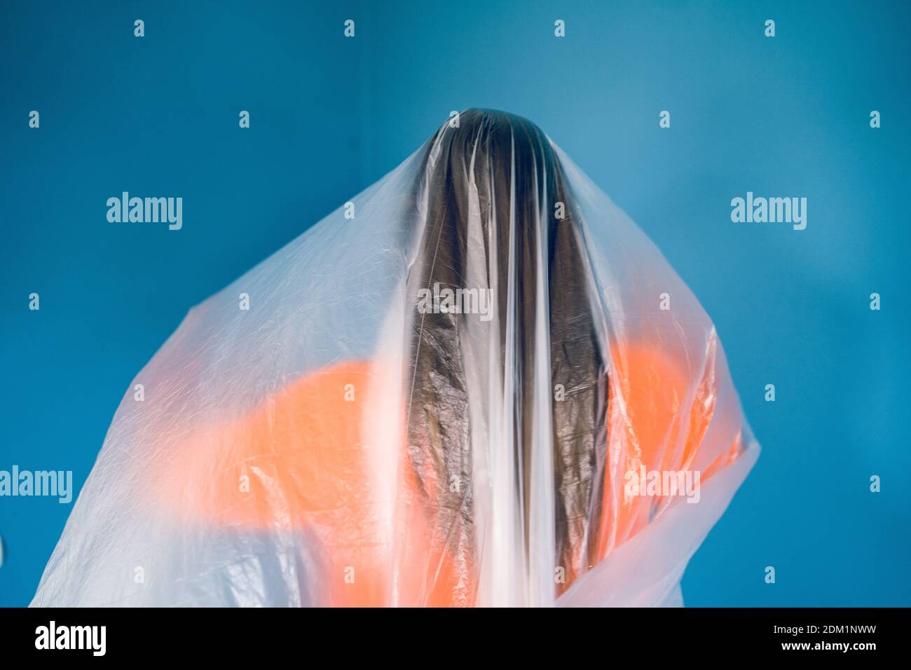 Woman Covered In Plastic Standing Against Blue Background Stock Photo ...