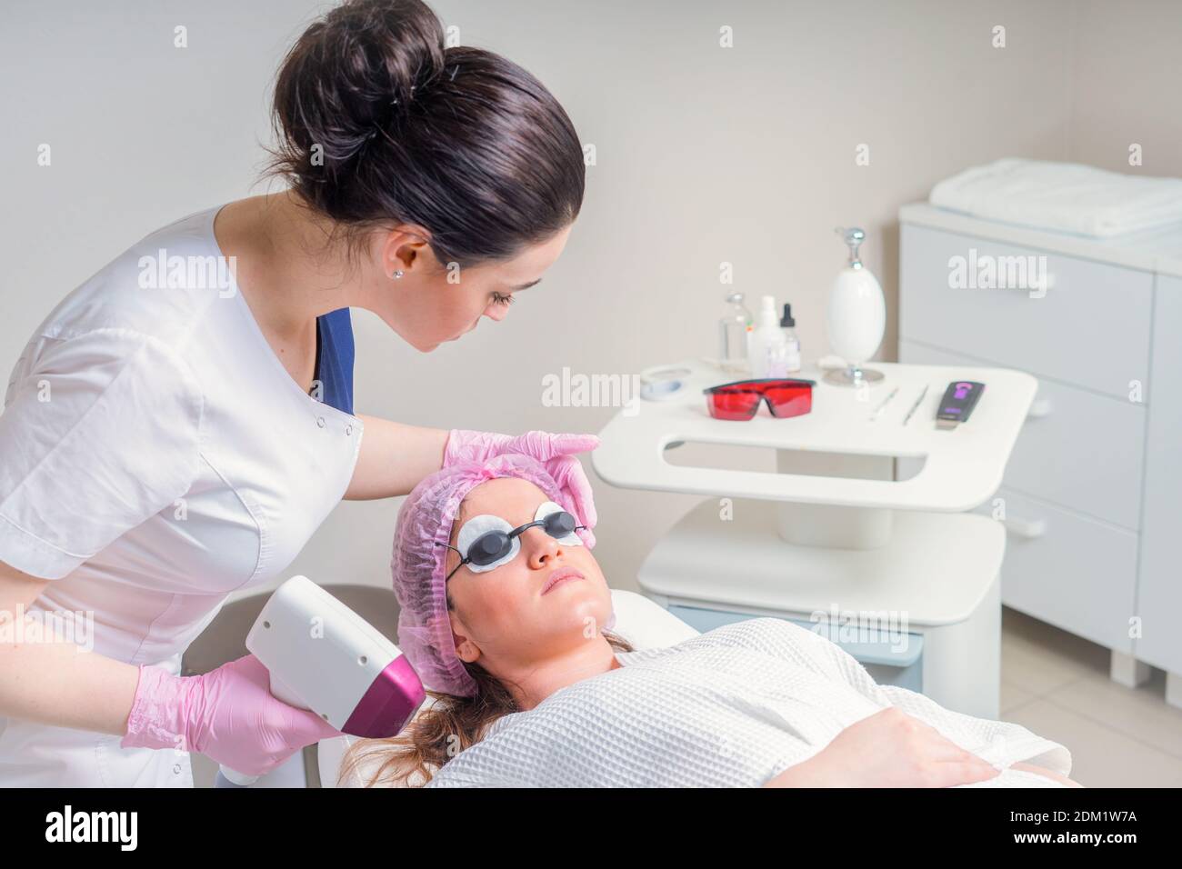 Young woman receiving laser treatment in cosmetology clinic. Eyes ...