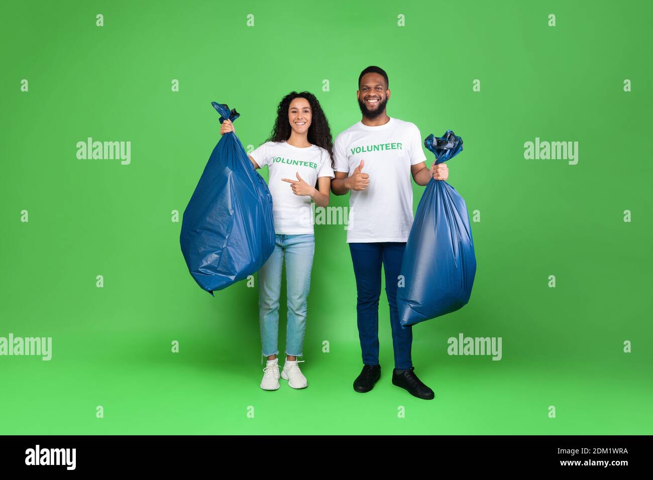 Two Diverse Volunteers Holding Garbage With Litter On Green Background ...