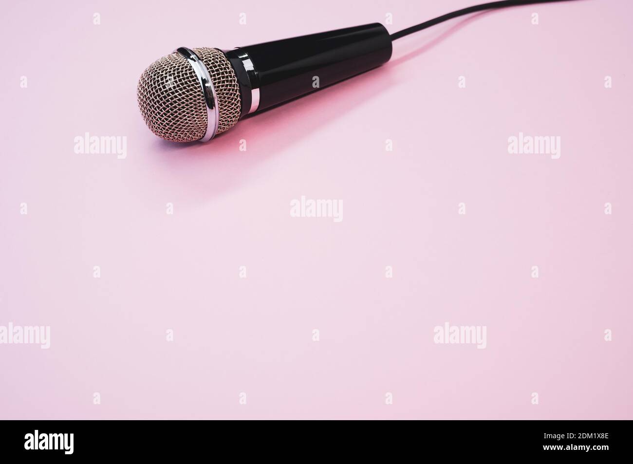 A closeup shot of a microphone with a wire isolated on a pink ...
