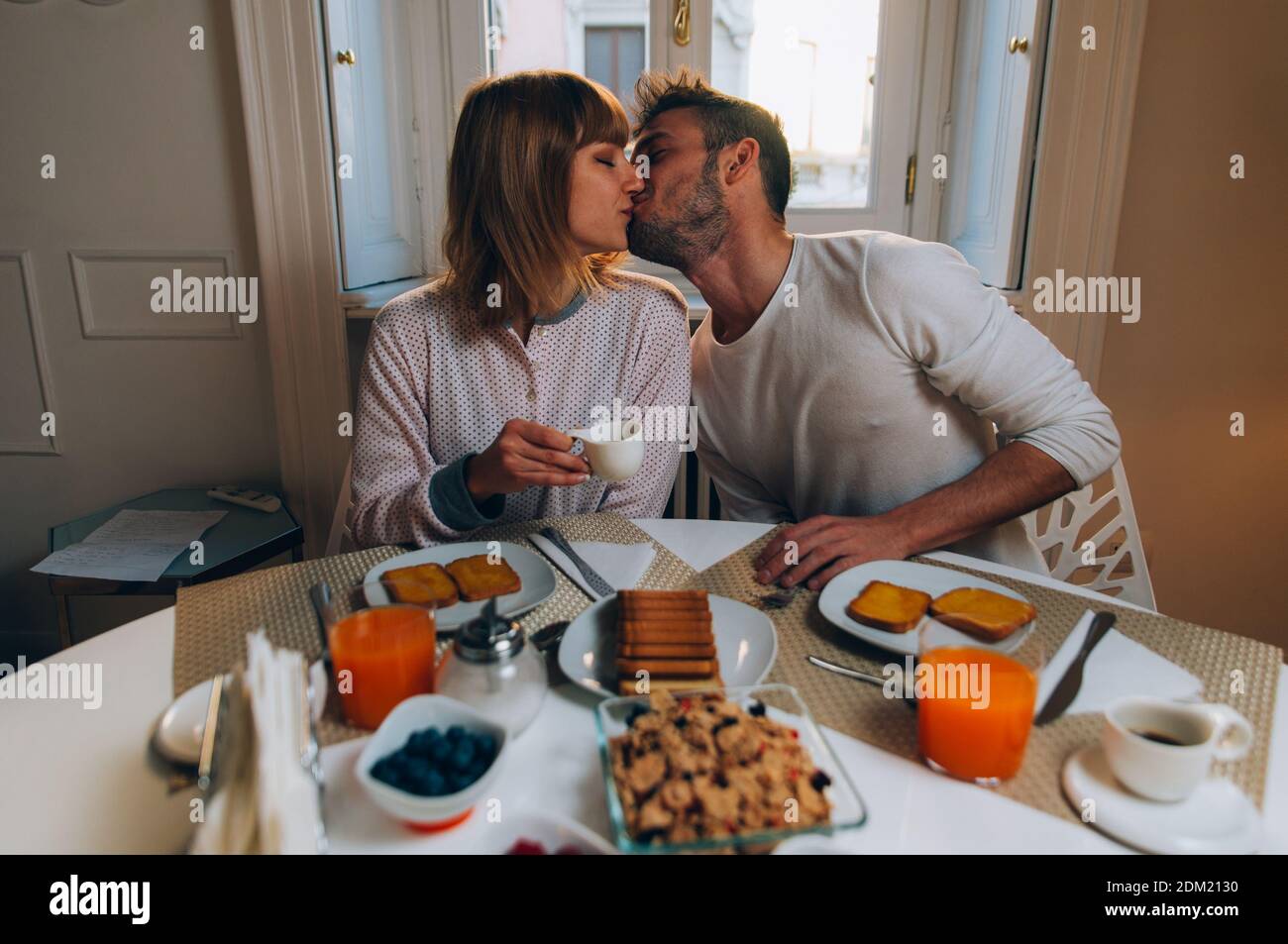 Young Couple Kissing While Having Breakfast At Home Stock Photo - Alamy