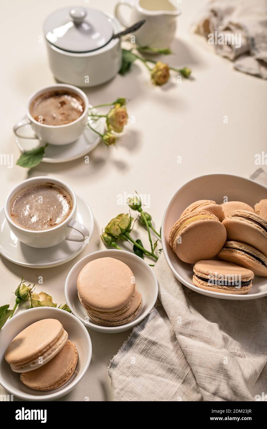 Frothy coffee in white cups, delicious French macaroons. Dessert still ...