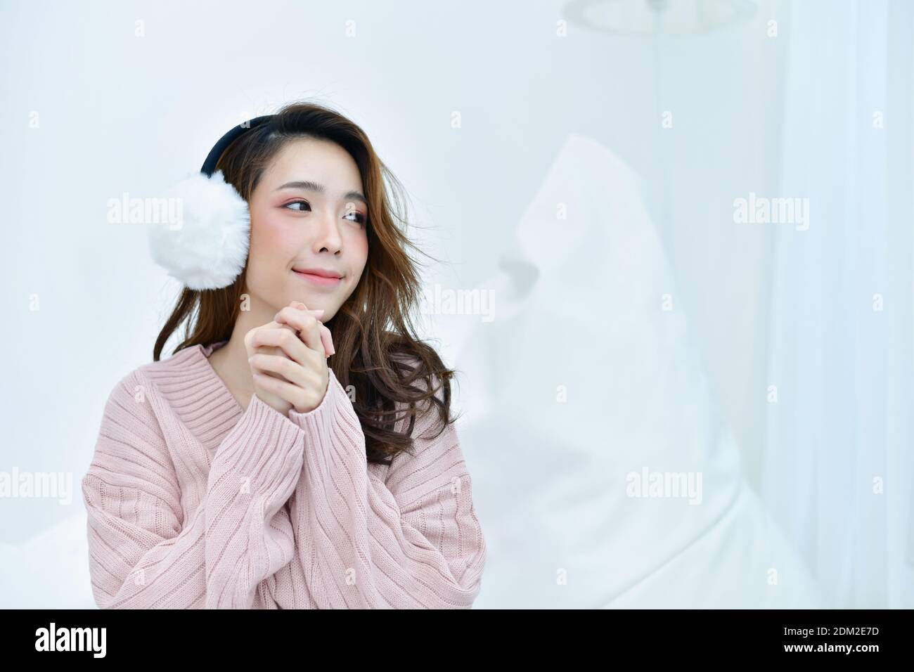 Woman Wearing Ear Puff On Bed At Home Stock Photo - Alamy