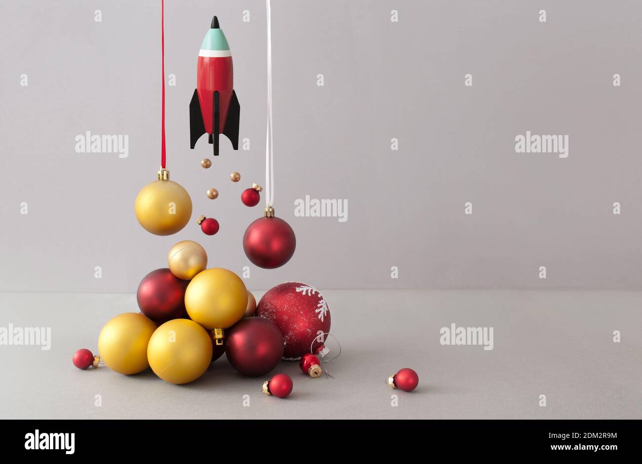 Toy rocket taking off with red and gold christmas baubles representing ...