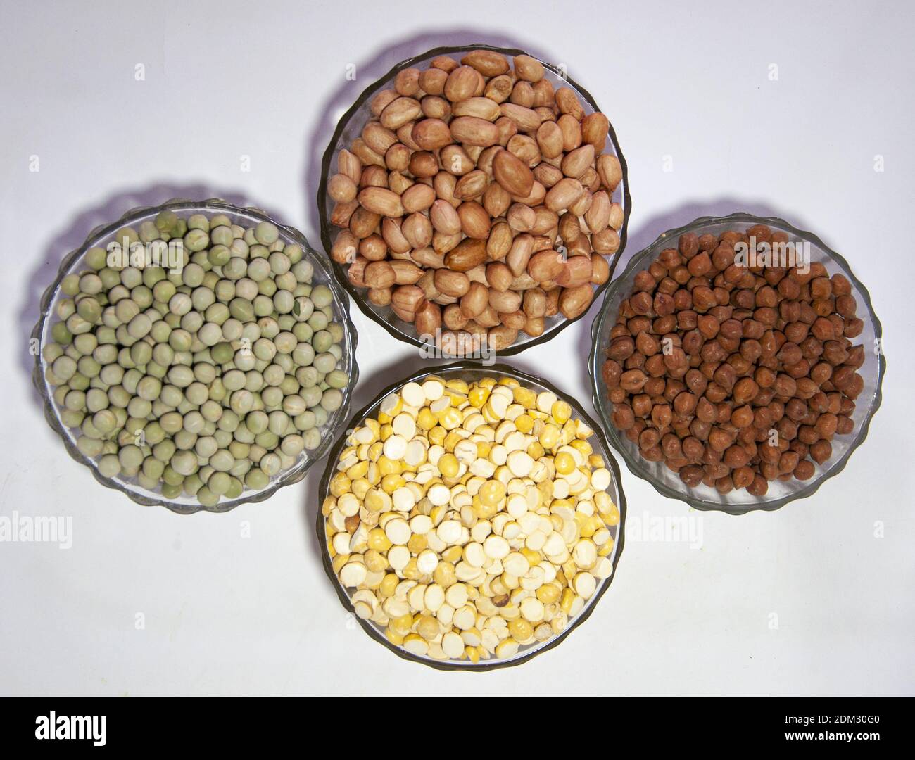 A top view of glass bowls with peanuts, corn, nuts and green peas ...