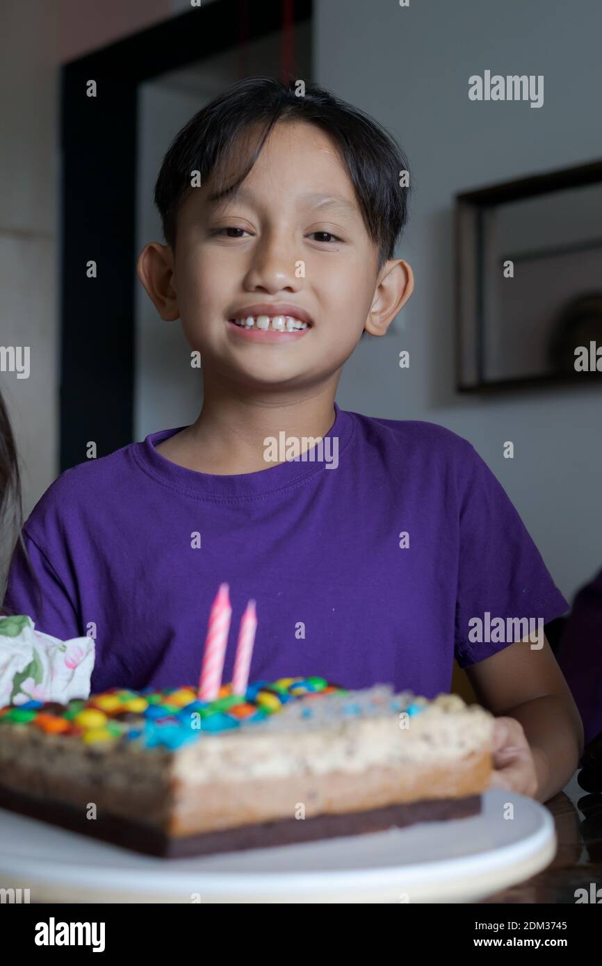 Asian boy blowing the candle of his birthday cake hi-res stock ...