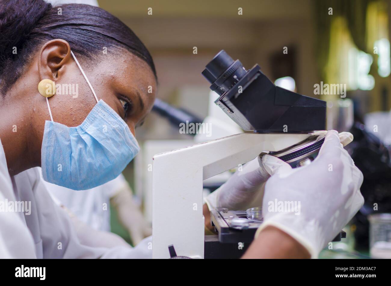 A young African scientist looking through a microscope in the ...