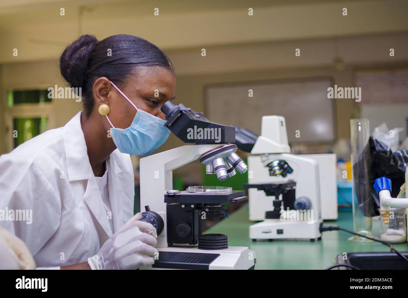 A young African scientist looking through a microscope in the ...