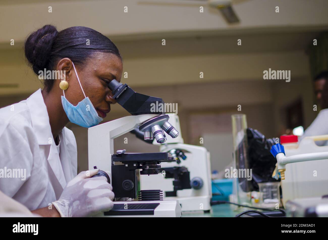 A young African scientist looking through a microscope in the ...