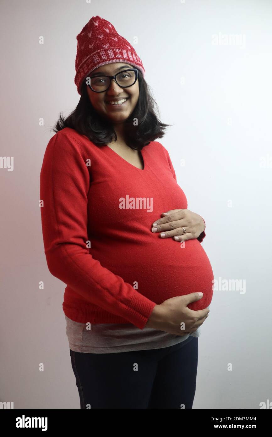 A vertical shot of a pregnant Indian female touching her belly Stock ...