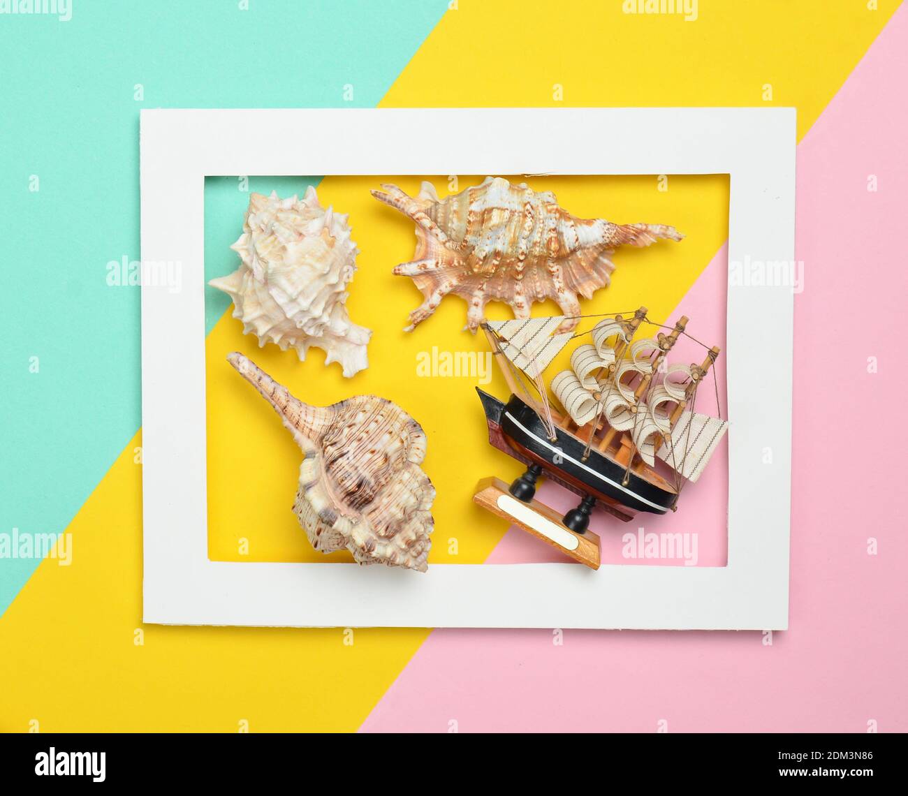 Seashells and decorative wooden ship in a white rectangular frame on a ...
