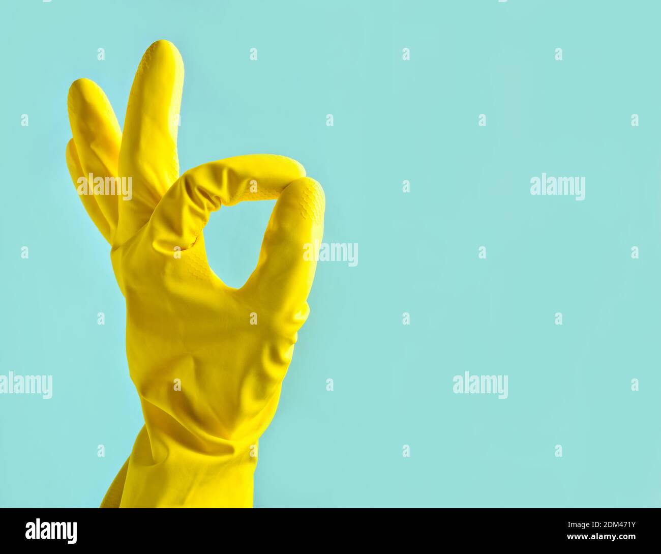 Hand in yellow rubber gloves shows thumbs symbol okay on blue ...