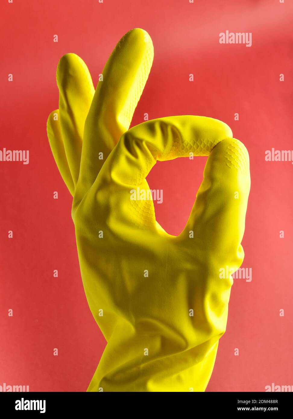 Hand with yellow rubber gloves shows thumbs symbol okay on red ...