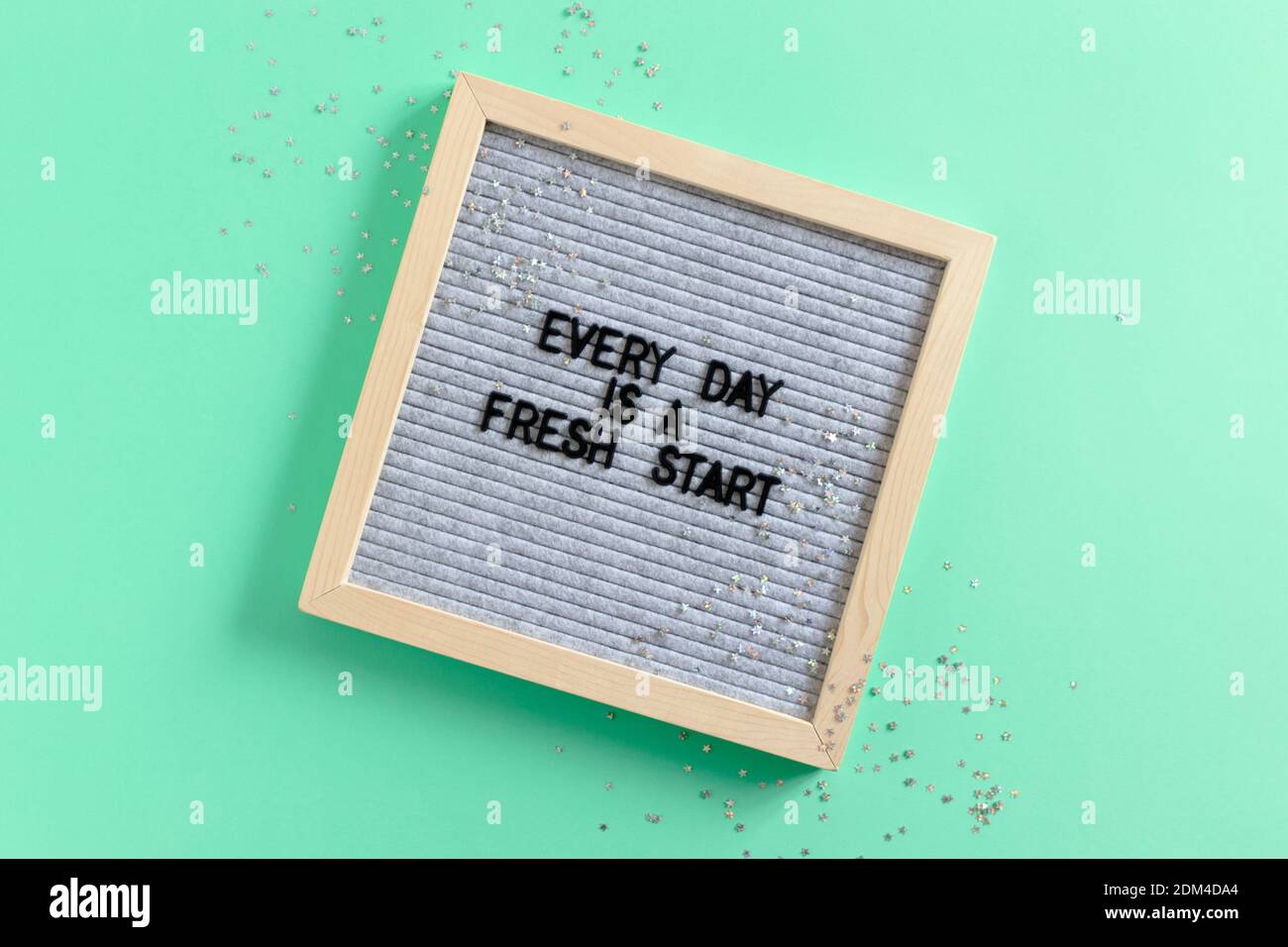 Letterboard with quote Every day is a fresh start and silver stars on ...