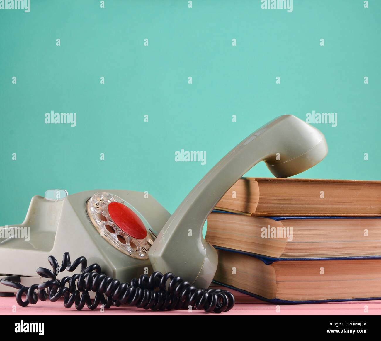 Retro rotary telephone, stack of books on a desk isolated against a ...