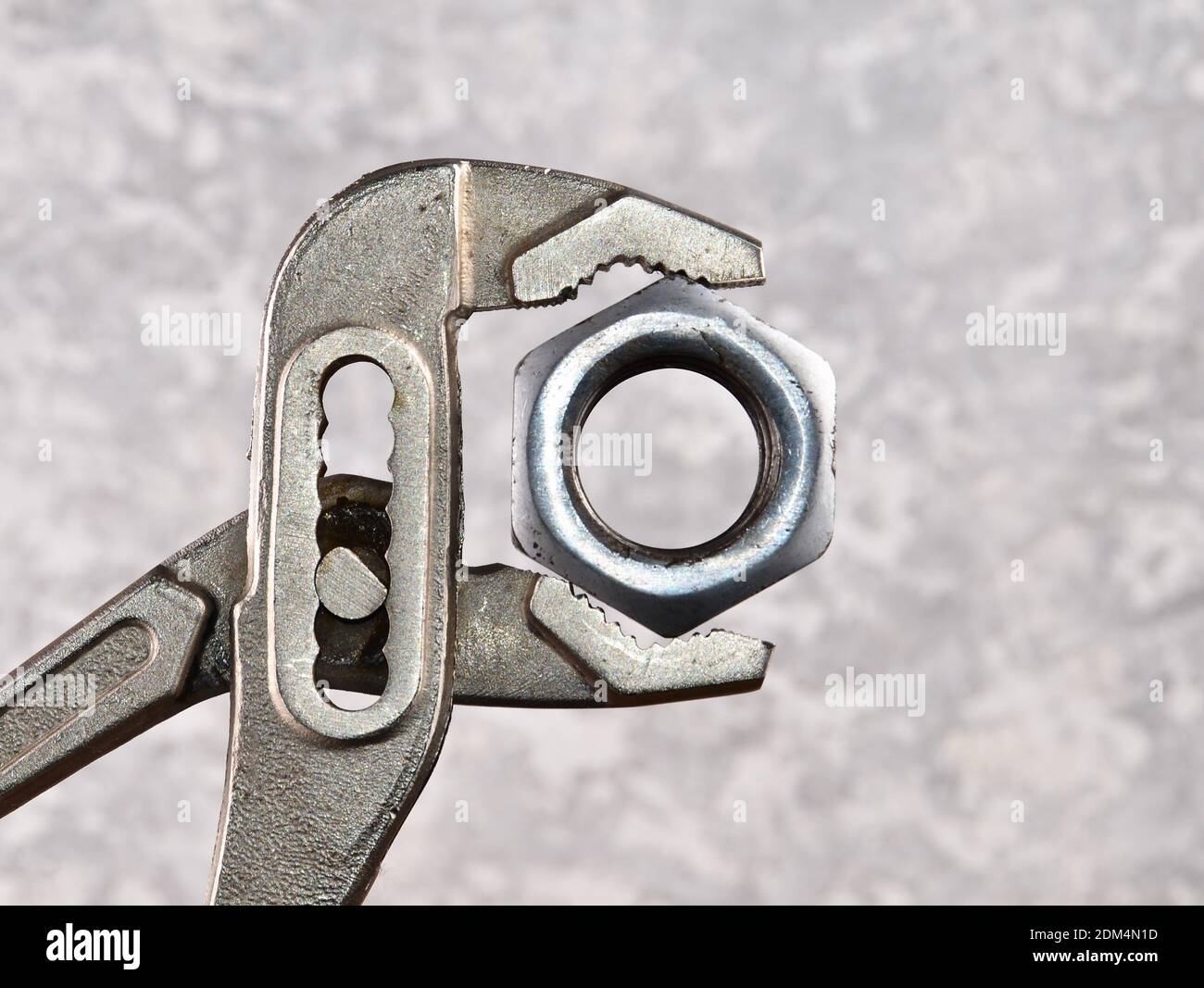 adjustable wrench with a nut on the background of a concrete wall Stock ...