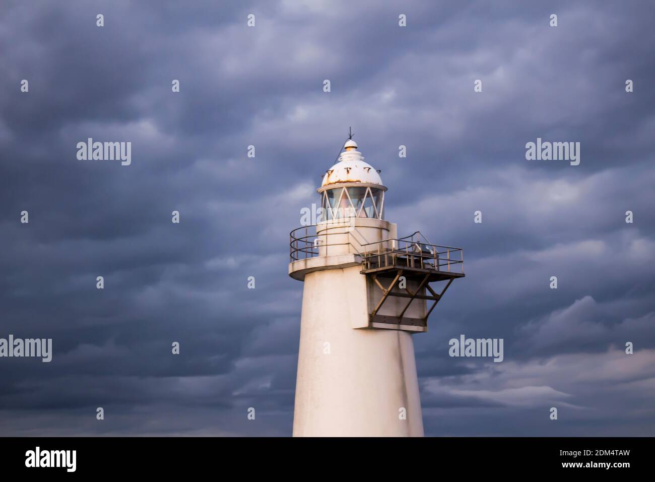White lighthouse towering under cloudy weather Stock Photo - Alamy
