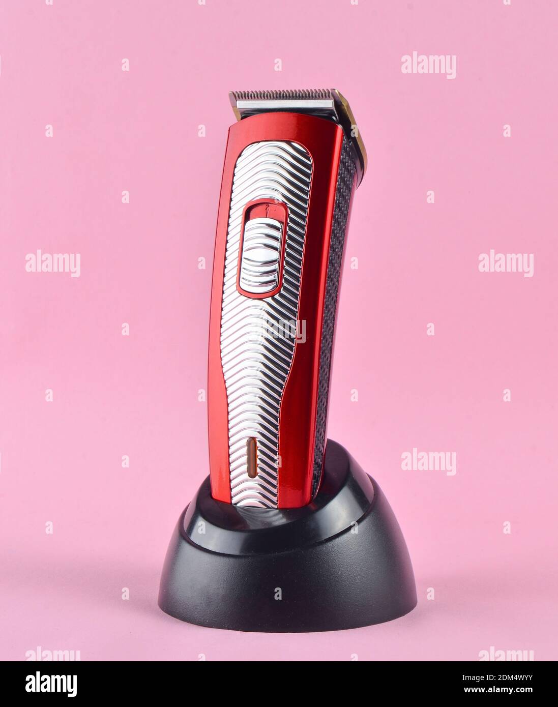 Wireless clipper stands at the charging station isolated on a pink ...