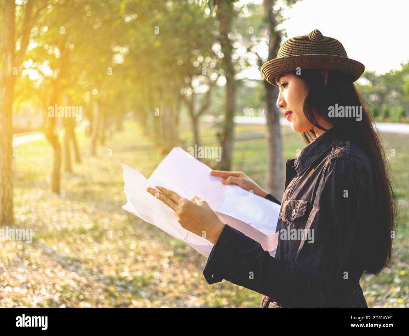 Side View Of Woman Reading Map While Standing Against Trees Stock Photo ...